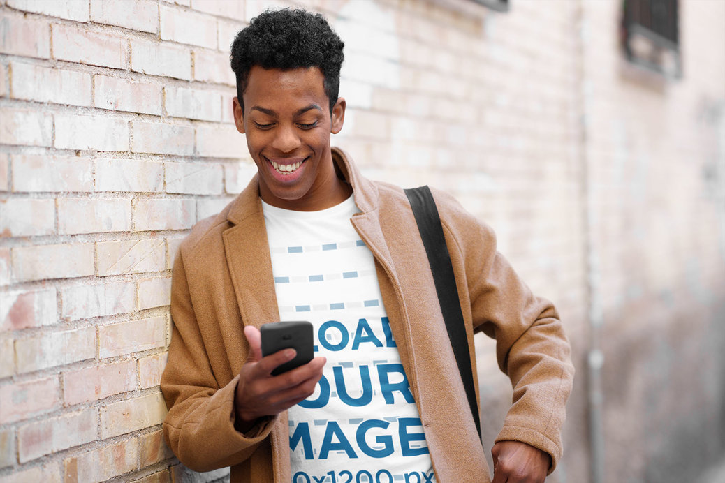 Placeit - T-Shirt Mockup of a Happy Man Checking His Phone on the Street