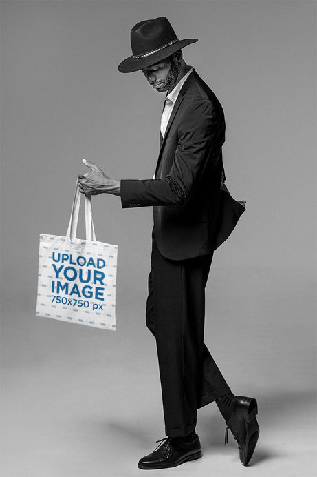 Placeit - Mockup of an Elegant Man Holding a Tote Bag at a Studio