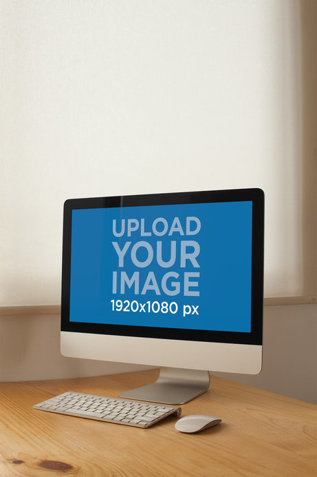 Placeit - Vertical Shot of an iMac Mockup Standing on a Wooden Desk