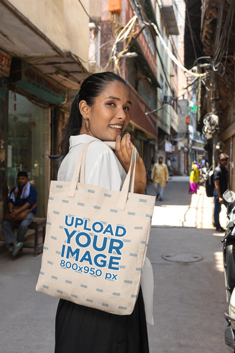 Placeit - Mockup of a Woman in an Alley Carrying a Tote Bag