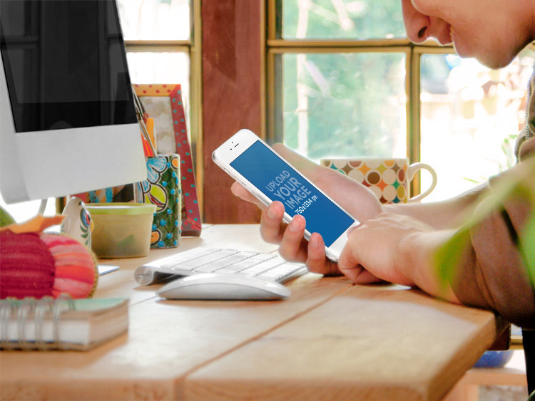 Placeit - Mockup of a Smiling Man Using an iPhone 6 While Working