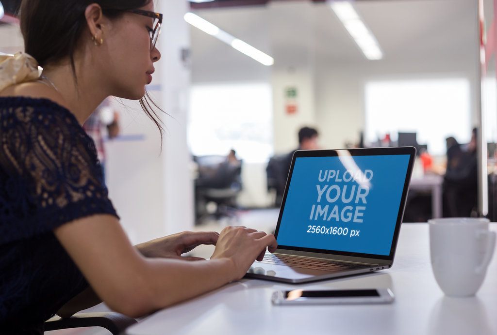 Placeit - Mockup of a Woman Working on her MacBook at a Modern Office