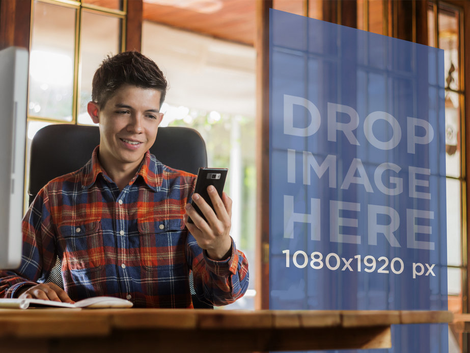 Placeit - Mockup of a Young Man Using Android Phone While Working