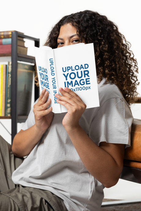 Placeit - Print Mockup Featuring a Woman Hiding Behind a Hardcover Book