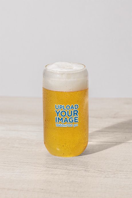Placeit - Drinkware Mockup Featuring a 16 Oz Can Glass Filled With Beer