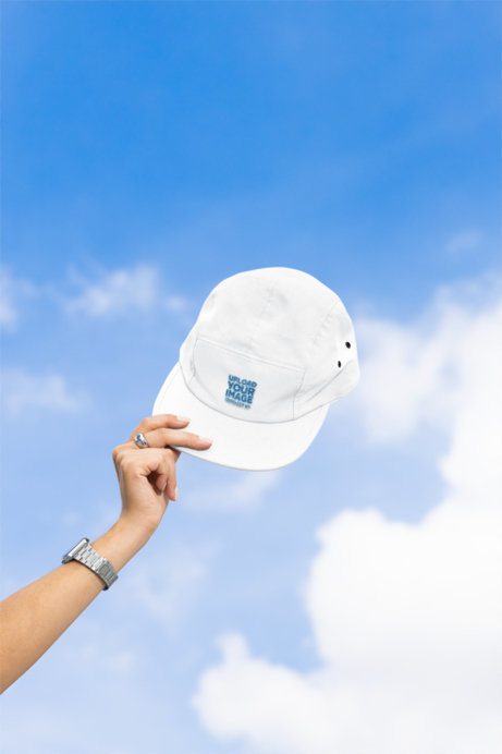 Placeit - Mockup of a Woman Holding a Yupoong Panel Cap Hat Against the Sky