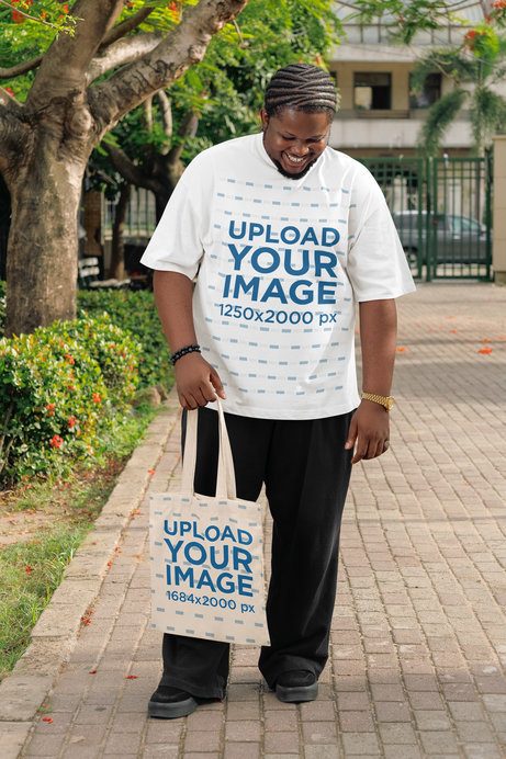 Placeit - Oversized T-Shirt Mockup of a Joyful Man Walking in the Street With a Sublimated Tote Bag