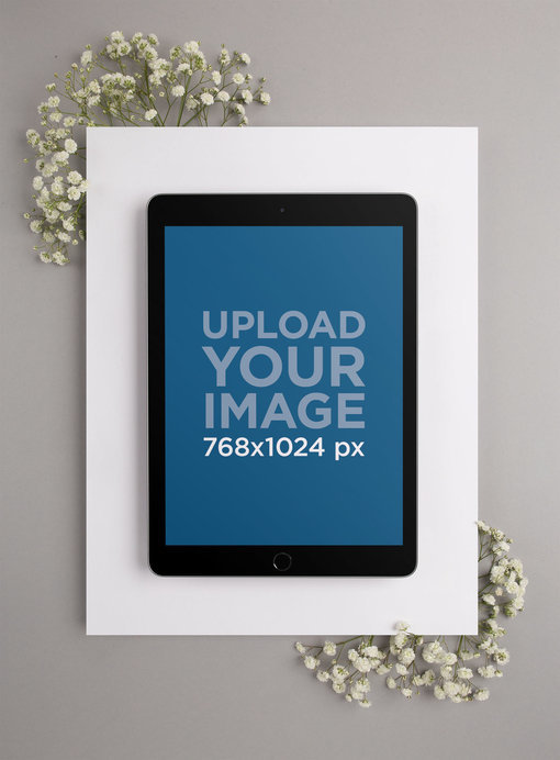 Placeit - iPad Mockup Lying Over a Blank Cardboard Bordered by Flowers