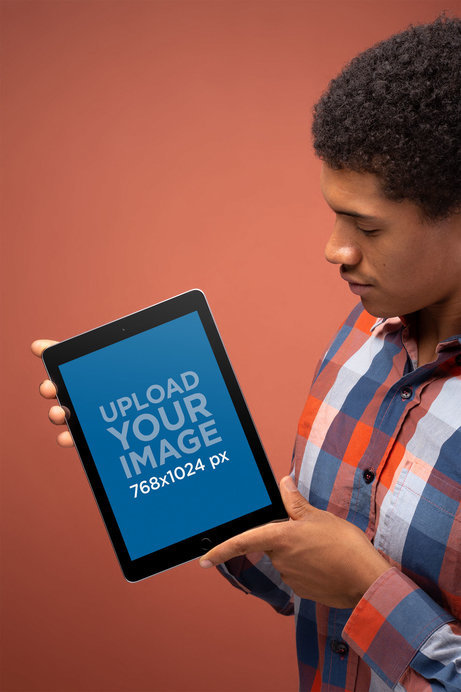 Placeit - Mockup of a Man Holding a Space Gray iPad in Portrait Position