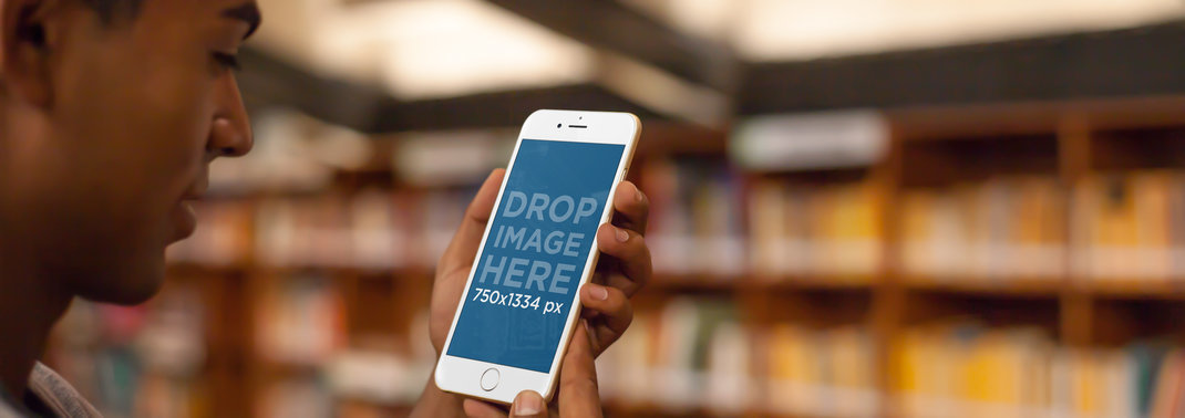 Placeit - Mockup of a Male Student Using an iPhone at his School Library