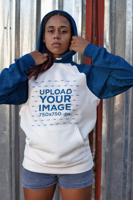 Placeit - Raglan Hoodie Mockup of a Woman Against a Metal Door