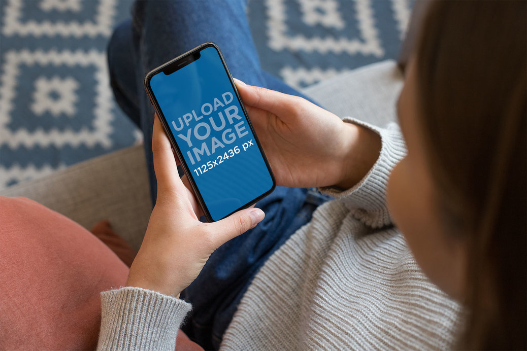 Placeit - Mockup of a Woman Sitting on a Couch Using Her iPhone 11 Pro