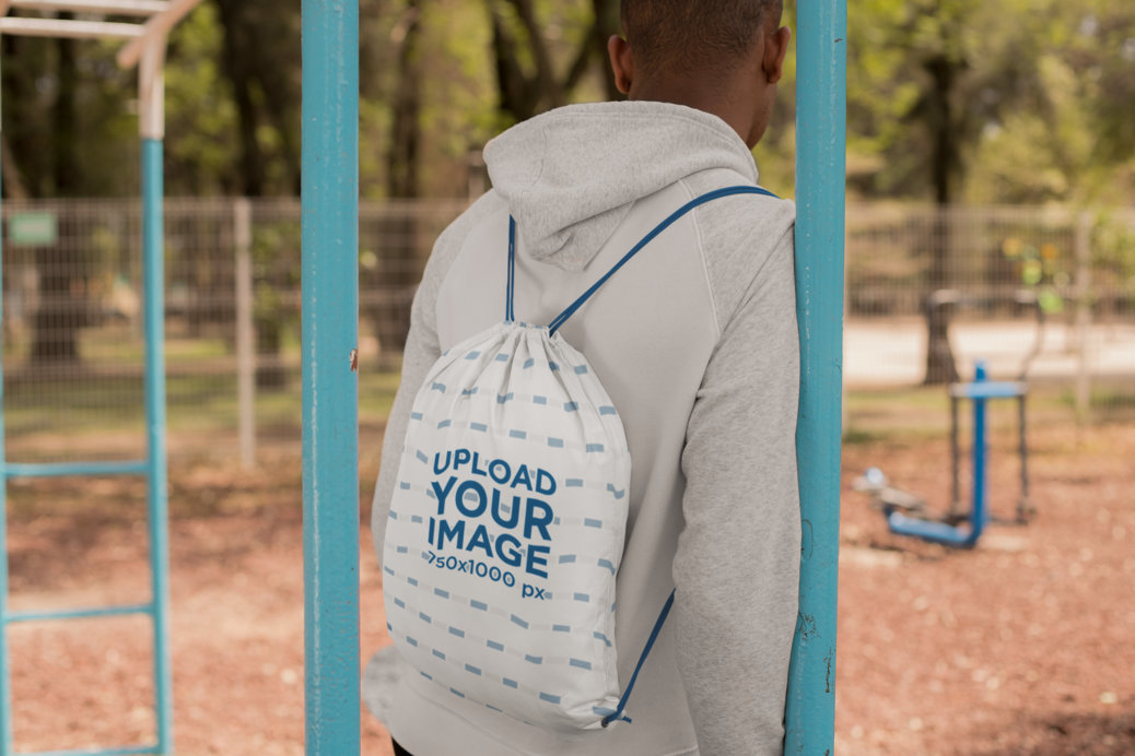 Placeit - Drawstring Bag Mockup of a Man at a Park Facing Backward