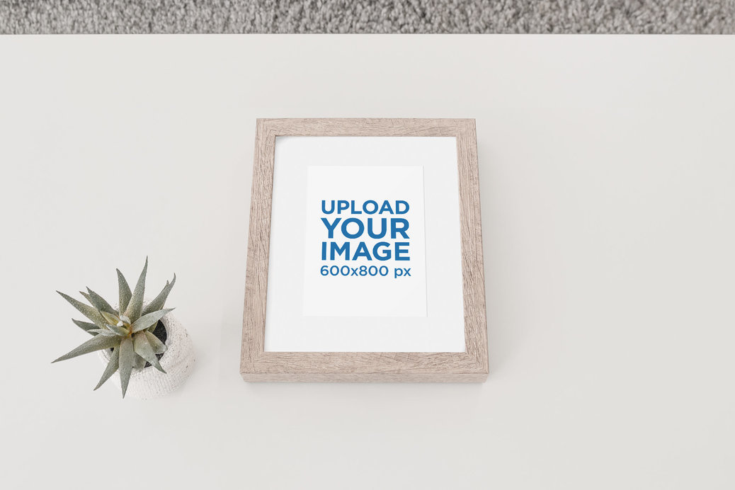 Placeit - Mockup of a Wooden Picture Frame Placed by an Indoor Plant Pot