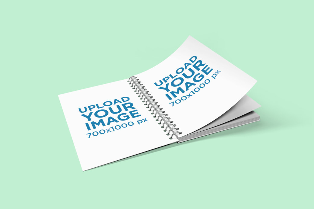 Placeit - Mockup Featuring an Opened Spiral Notebook Lying Against a Solid Color Backdrop