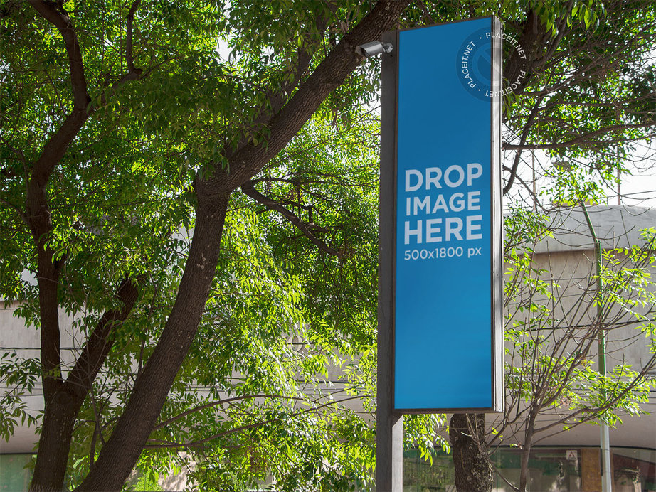 Placeit - Vertical Banner Mockup in the Street Next to a Tree