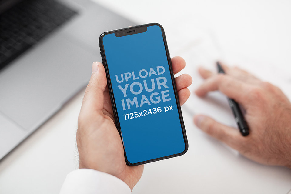 Placeit - Mockup of a Man Holding an iPhone 11 While Working
