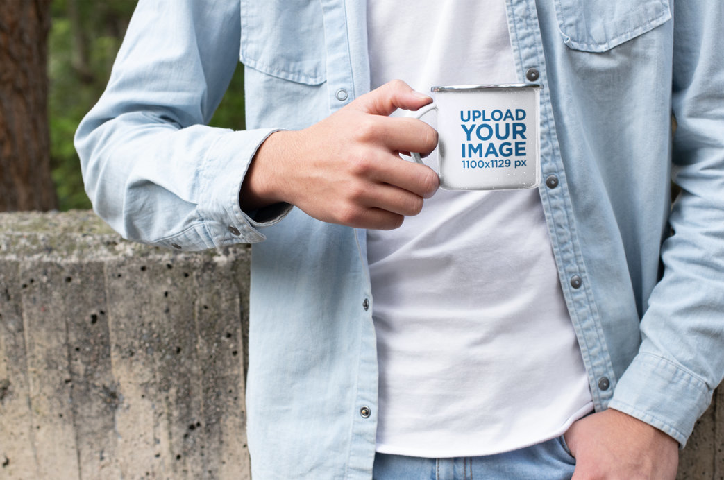 Placeit - Mockup of a Man Holding a 12 oz Enamel Mug with Silver Rim