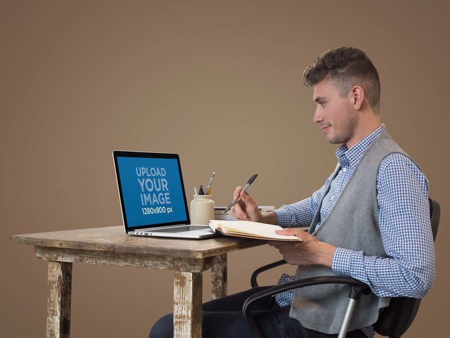 Placeit - MacBook Pro Mockup of a Man Writing in His Notebook