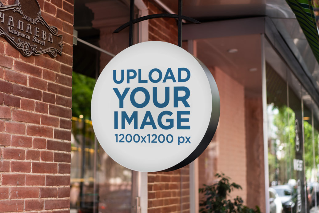 Placeit - Mockup of a Circular Sign by a Brick-Wall Store