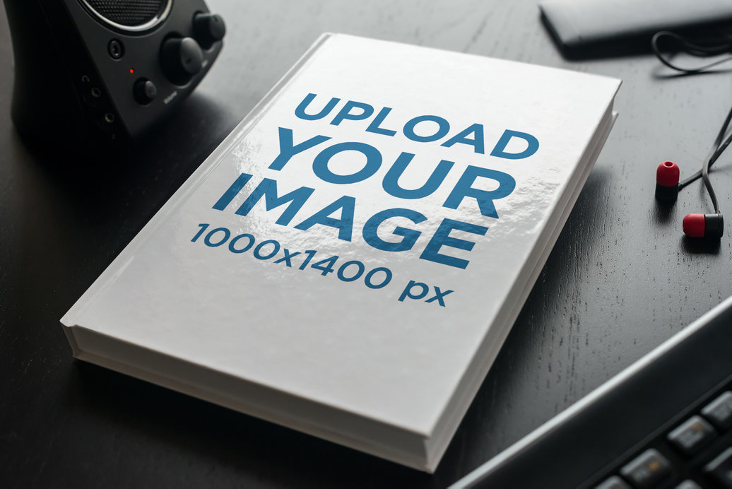Placeit - Mockup of a Hard Cover Book on a Table with Gadgets