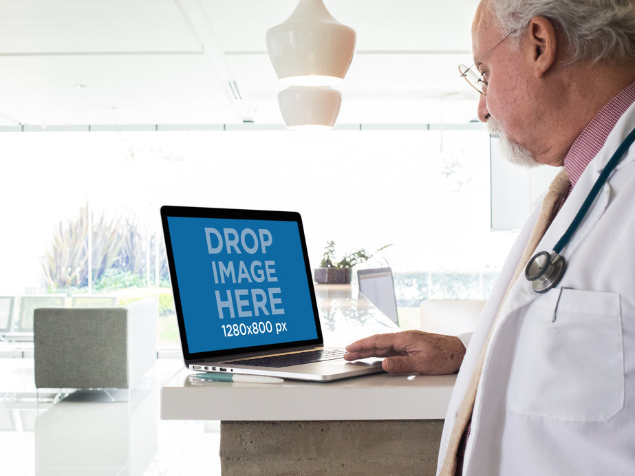 Placeit - Mockup of a Senior Male Doctor with a MackBook at a Hospital