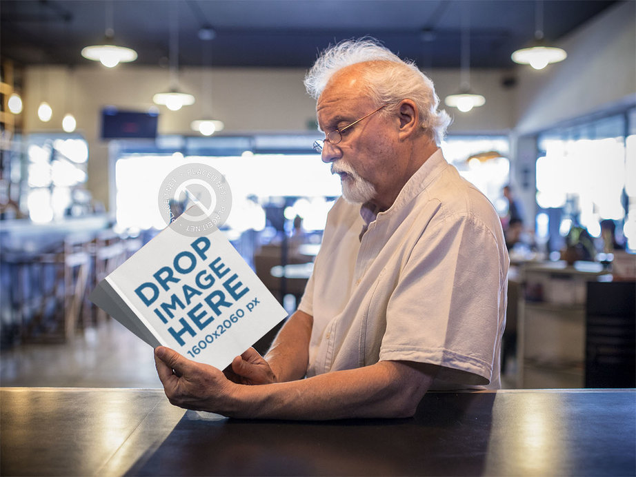 Placeit - Old Man Reading a Book While Lying on a Coffee Table Mockup