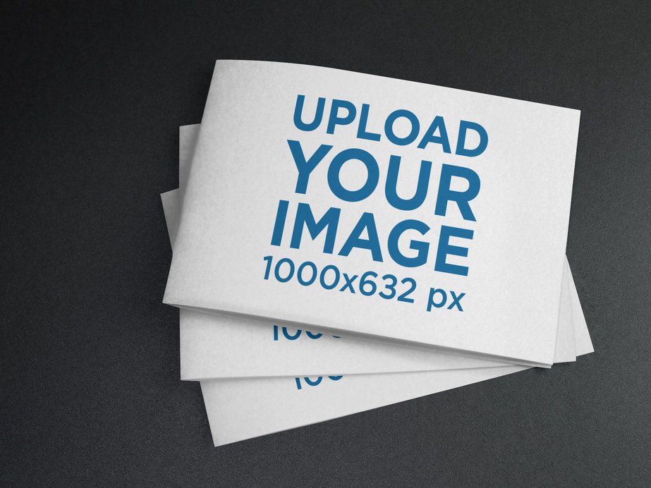 Placeit - Mockup of Three Small Catalogs Stacked on a Black Surface