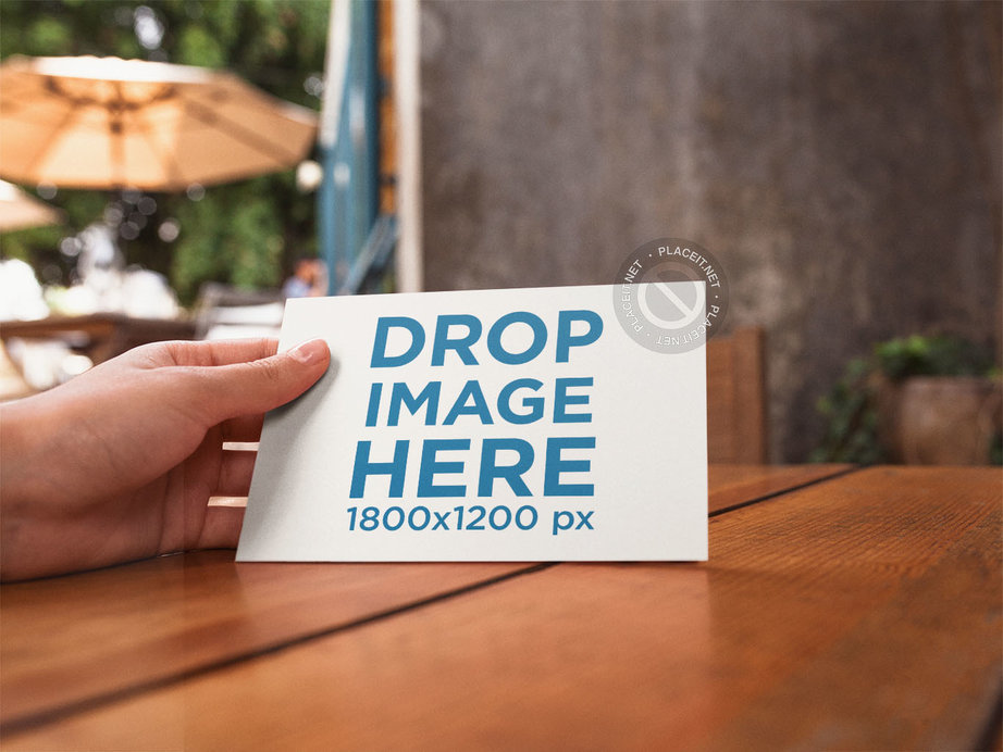 Placeit - Postcard Template Being Read on a Wooden Table at a Cafe