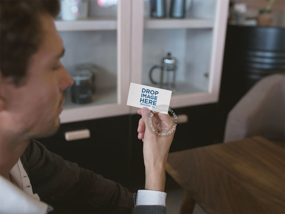 Placeit - Young Man Holding a Business Card Template in a Coffee Shop
