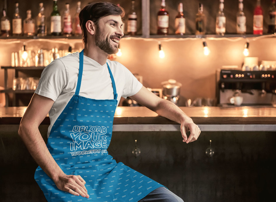 Placeit - Apron Mockup Featuring a Smiling Man Sitting at a Bar